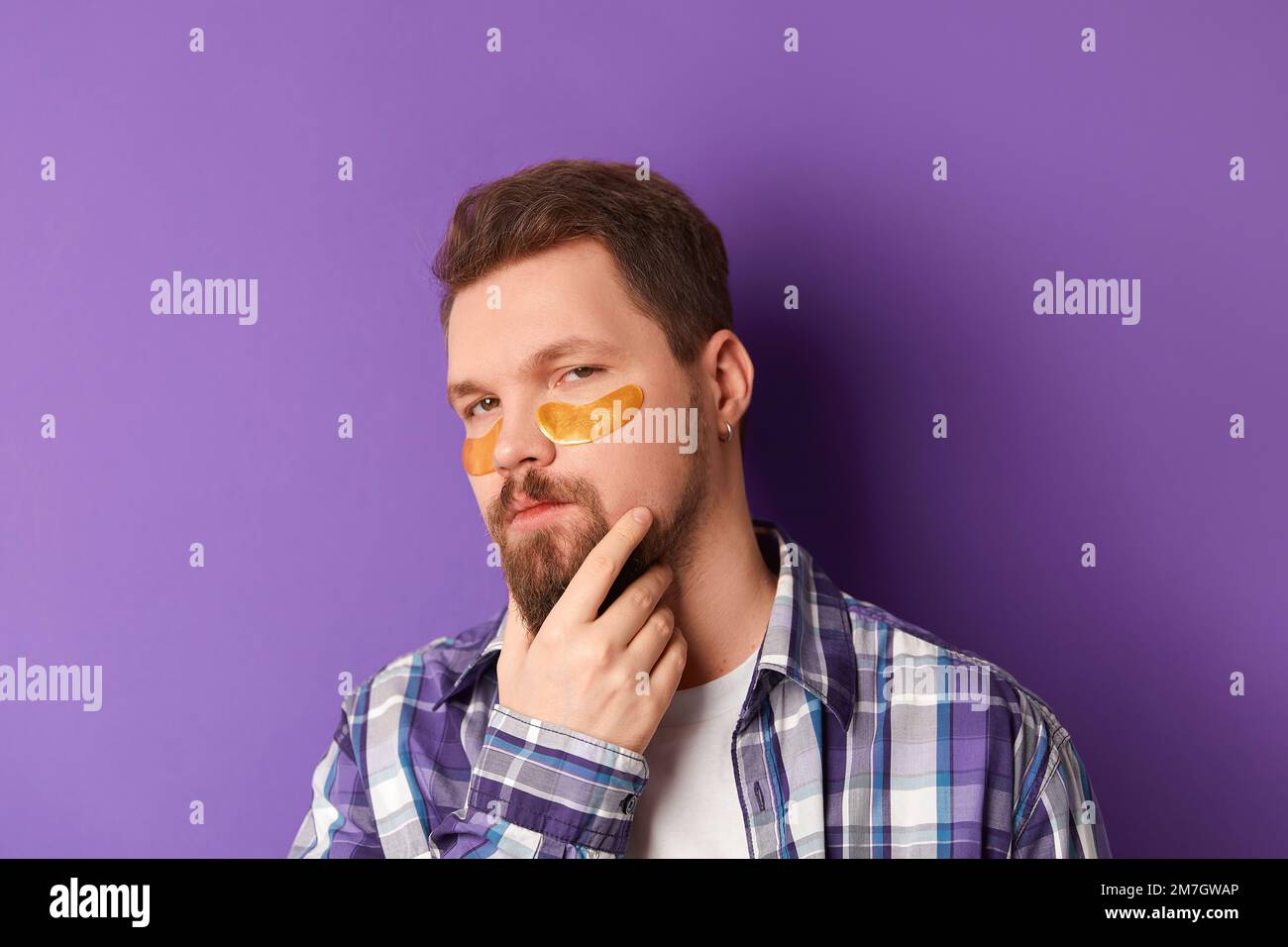 Man in white tshirt with eye patches stand against violet background ...