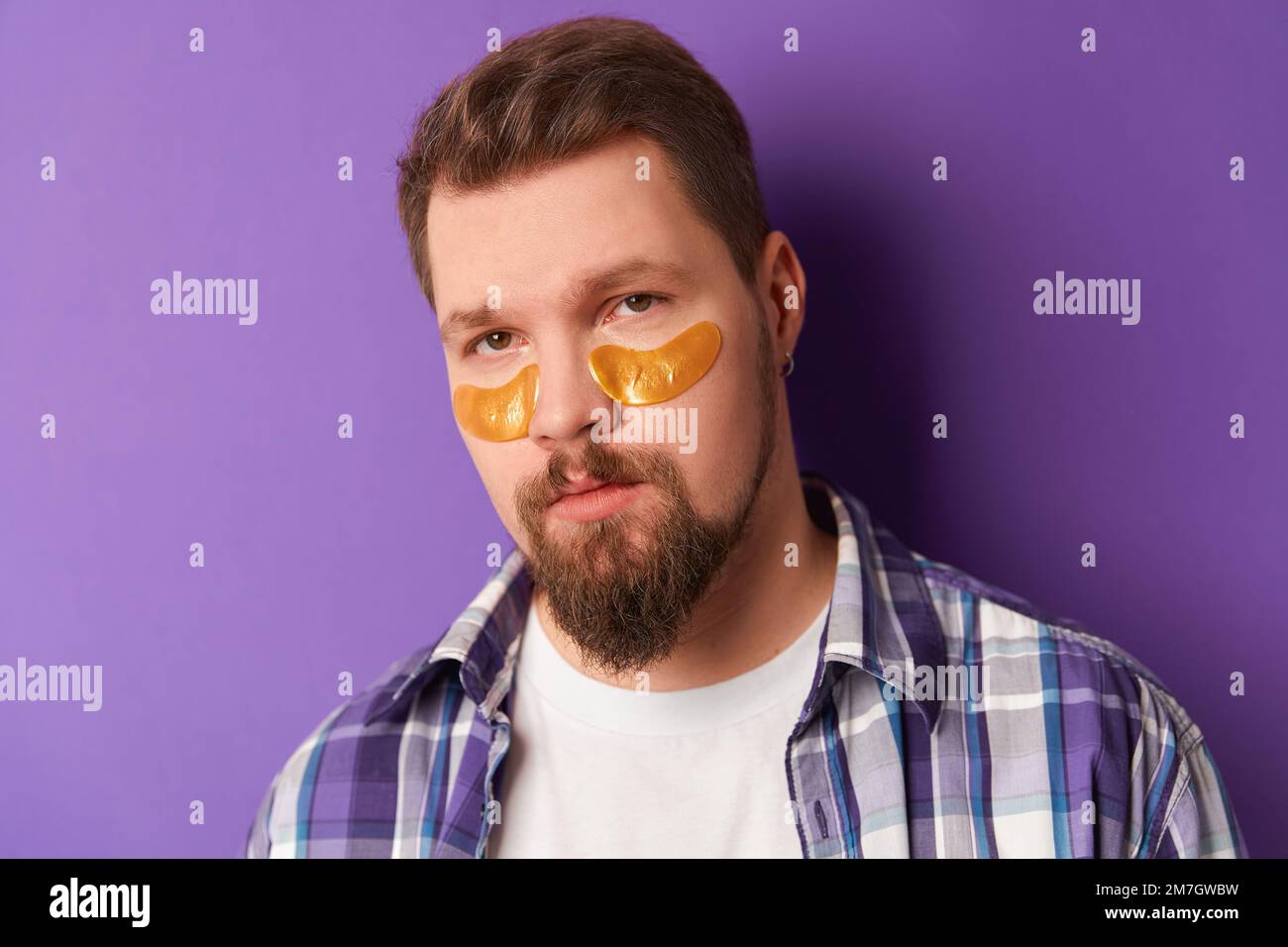 Man in white tshirt with eye patches stand against violet background ...