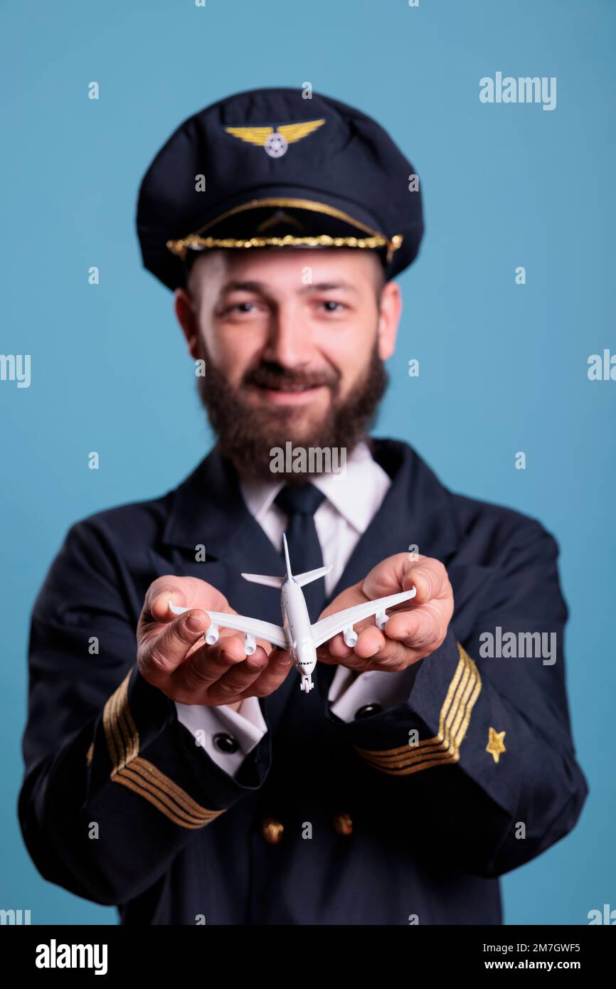 Portrait of airplane aviator in uniform holding plane toy in palms ...