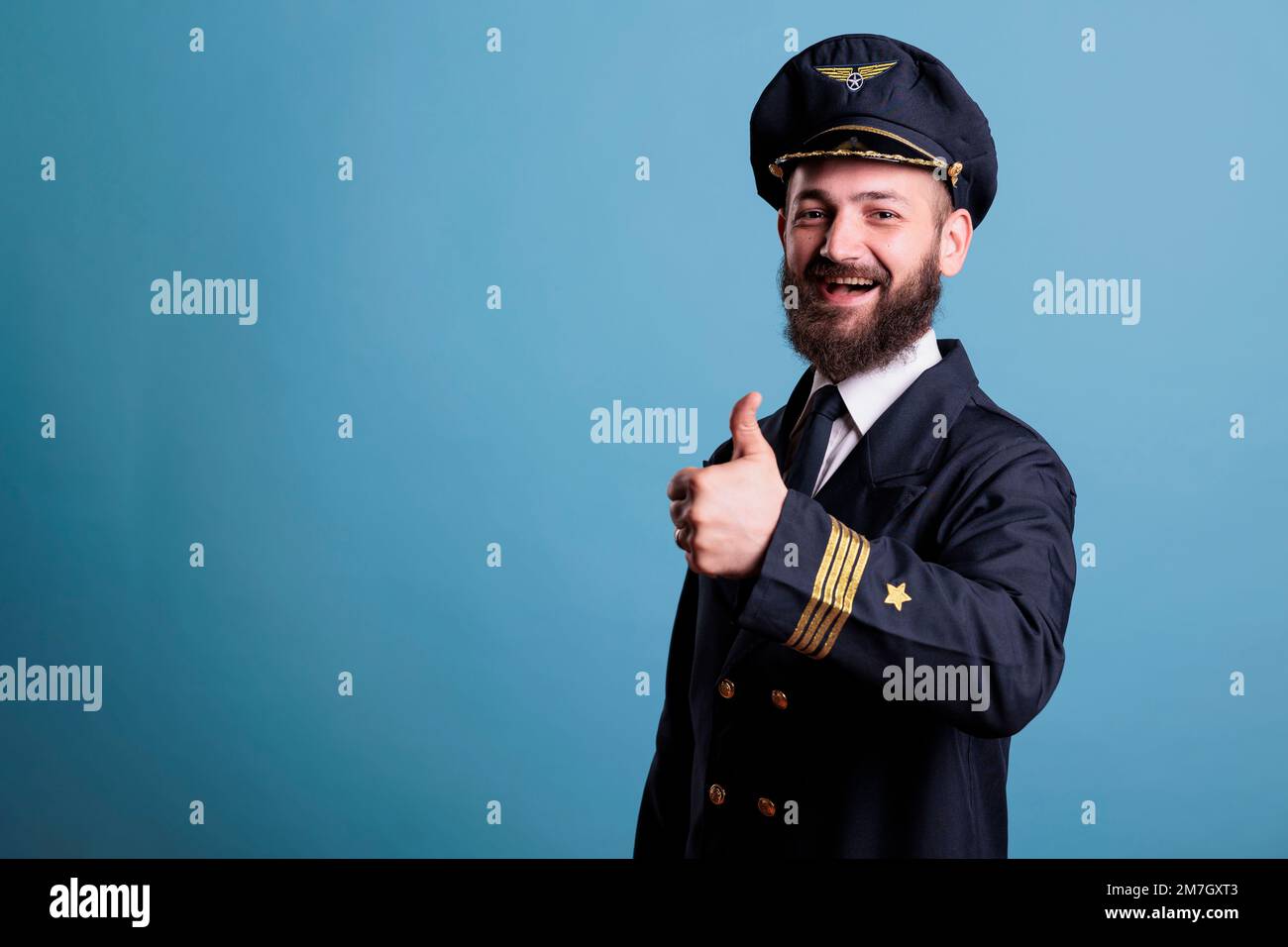 Smiling airplane pilot with thumb up gesture wearing professional ...