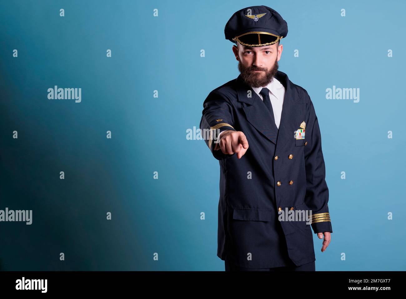 Serious aircraft pilot pointing at camera, plane aviator wearing ...