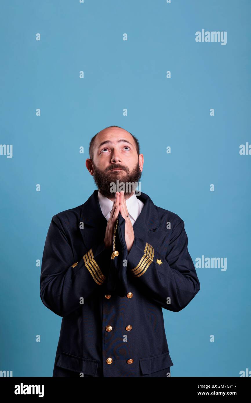 Airline pilot in uniform praying to gods, looking upwards, standing ...