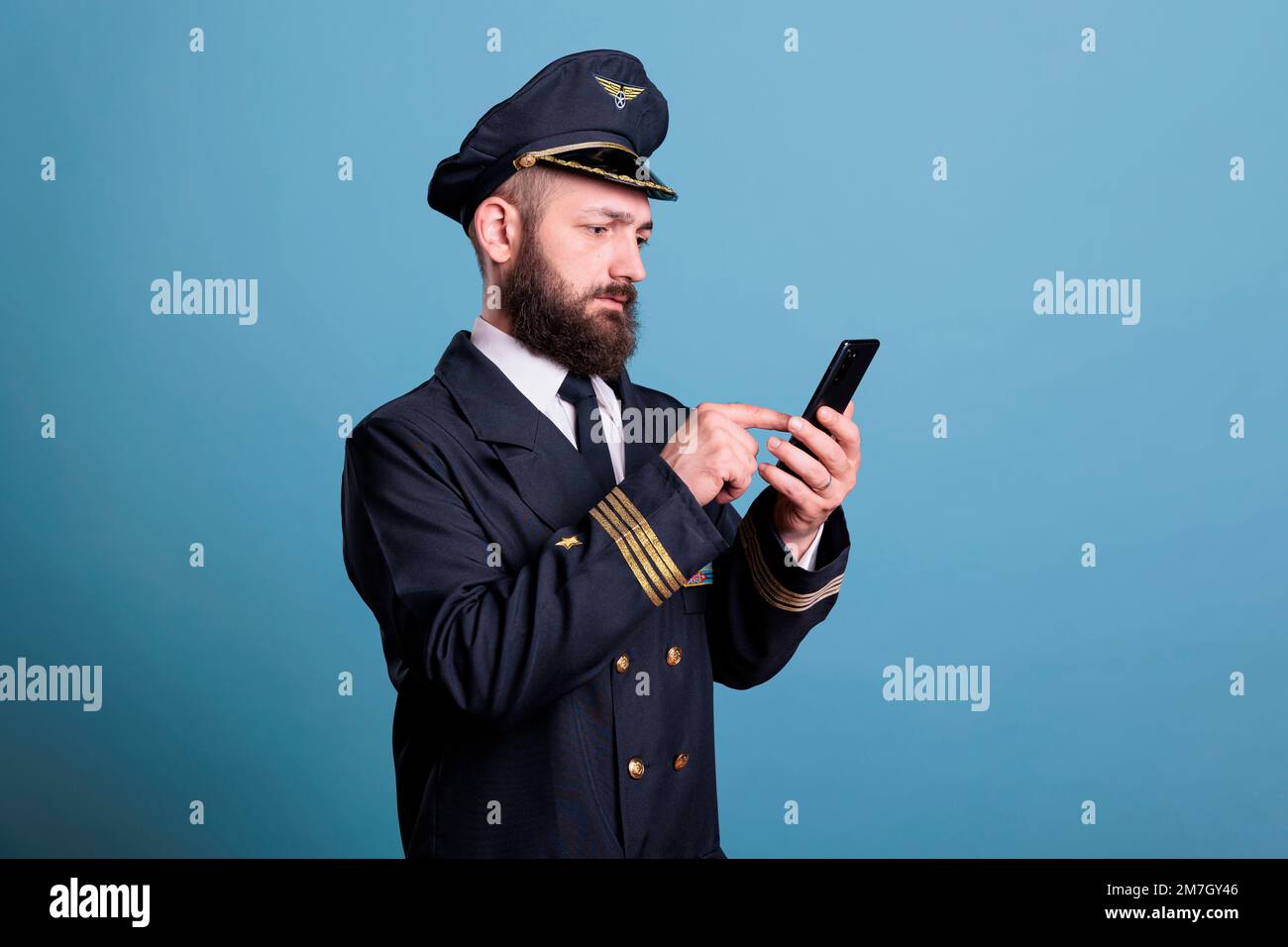 Plane aviator in aviation uniform watching online video on smartphone ...