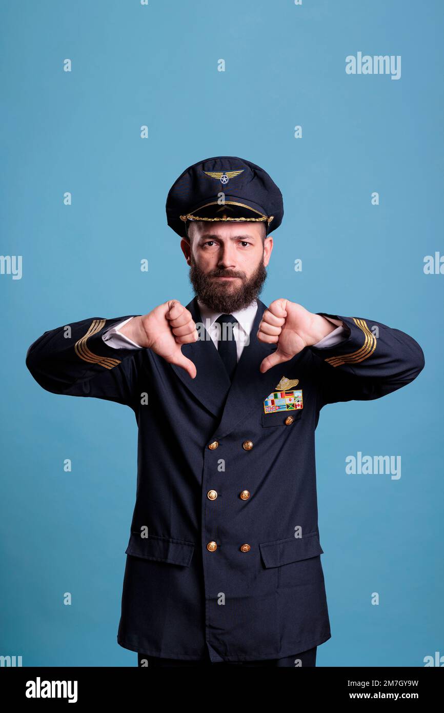 Serious airplane pilot with thumbs down gesture wearing professional ...