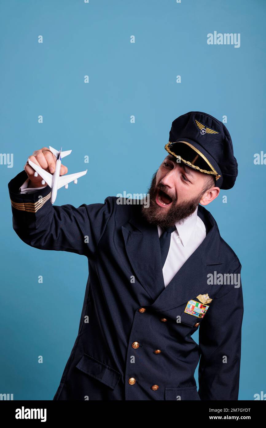 Pilot in uniform playing with airplane model, aviation academy aviator ...