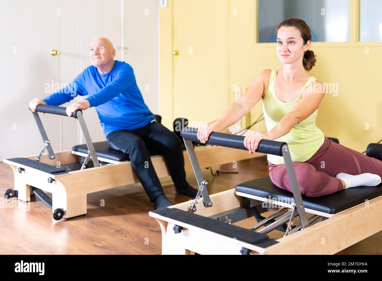 Positive woman practicing pilates stretching exercises on reformer ...