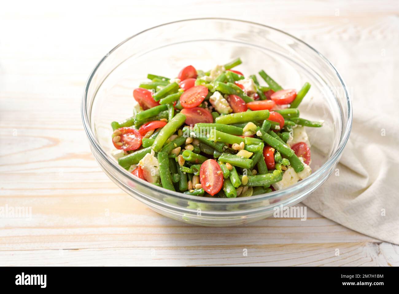 Green bean salad with tomatoes, pine nuts and feta cheese in a glass ...