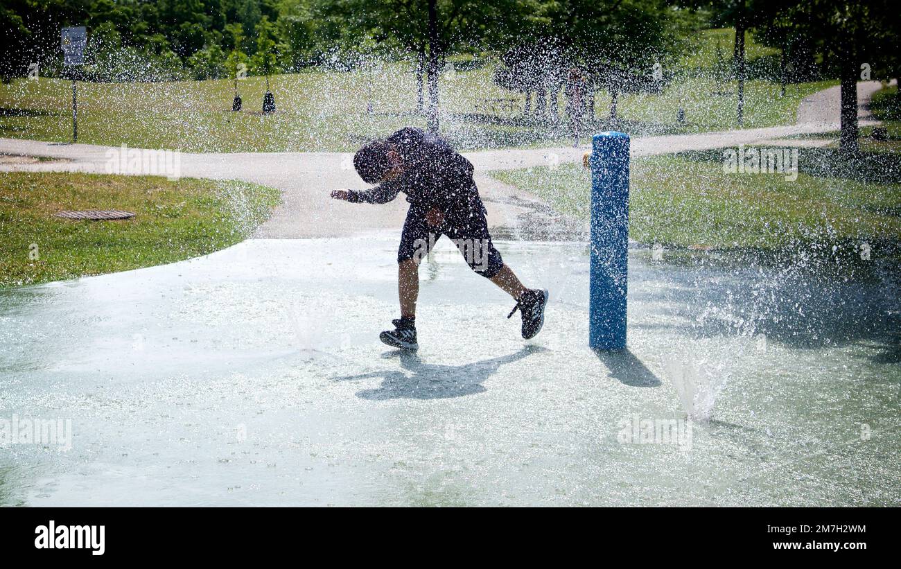 In a hot summer day, a boy running between the sprinkler. Outdoor fun ...