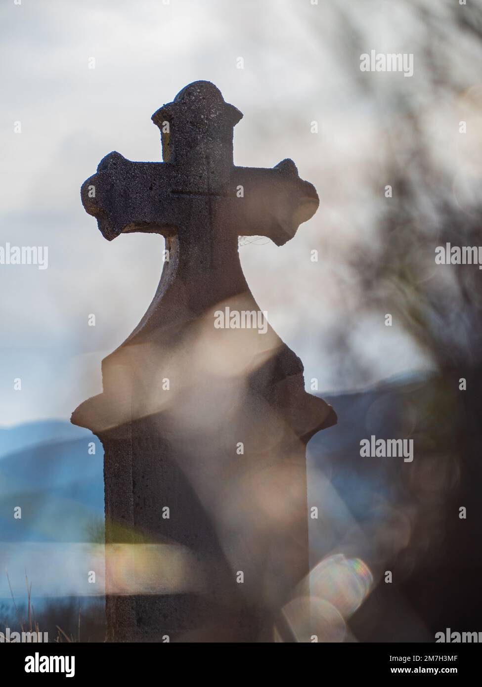 Old cross vintage tombstone standing on a grass field sunshine clouds ...