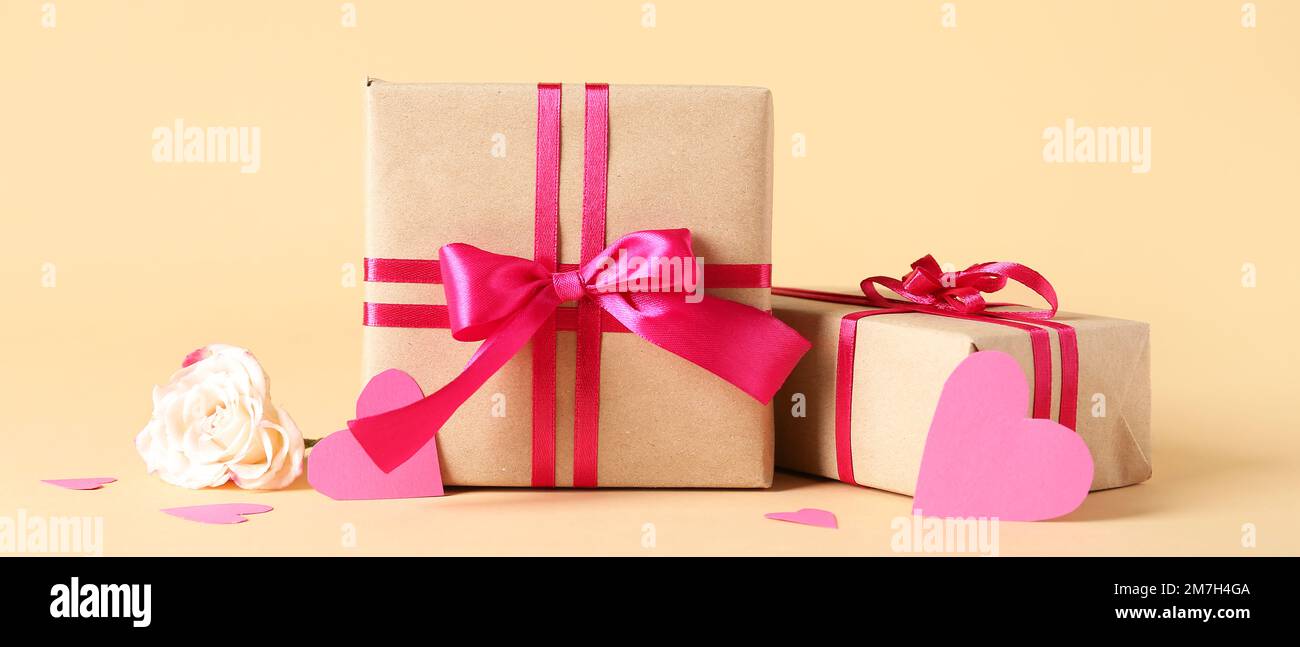 Gift boxes, rose flower and paper hearts on beige background. Valentine ...