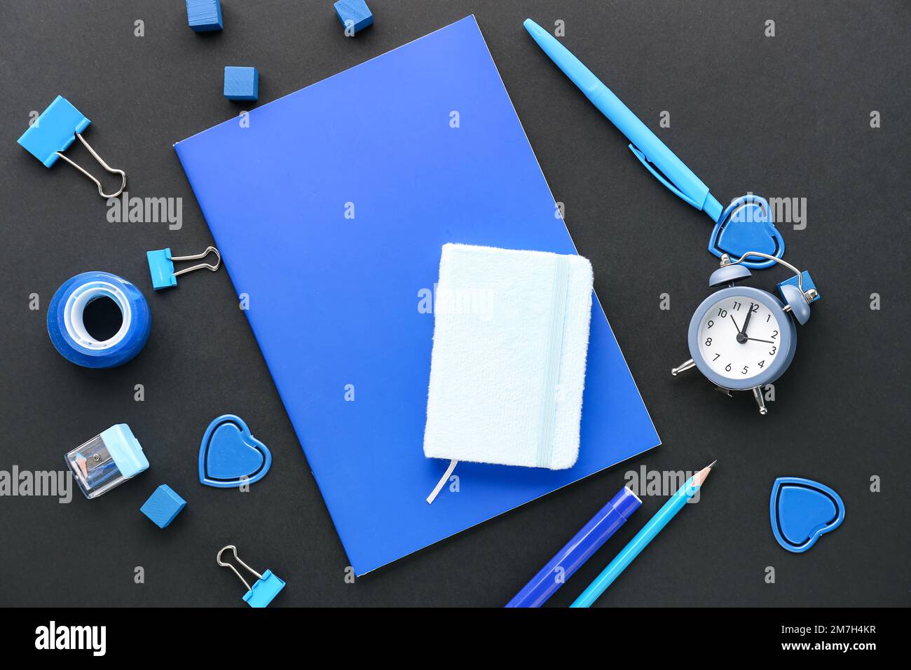 Set of blue stationery with notebooks and alarm clock on dark ...