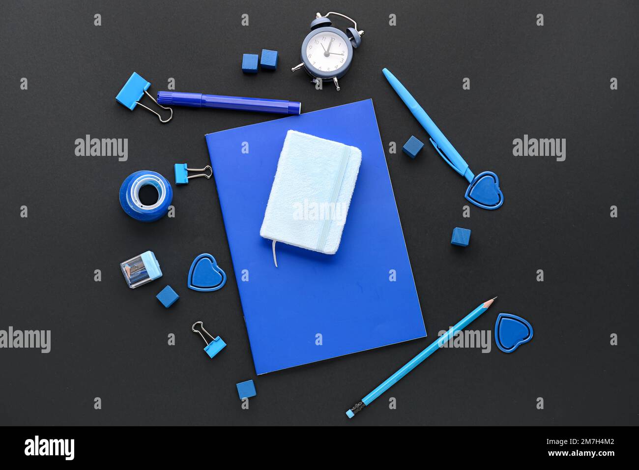 Set of blue stationery with notebooks and alarm clock on dark ...