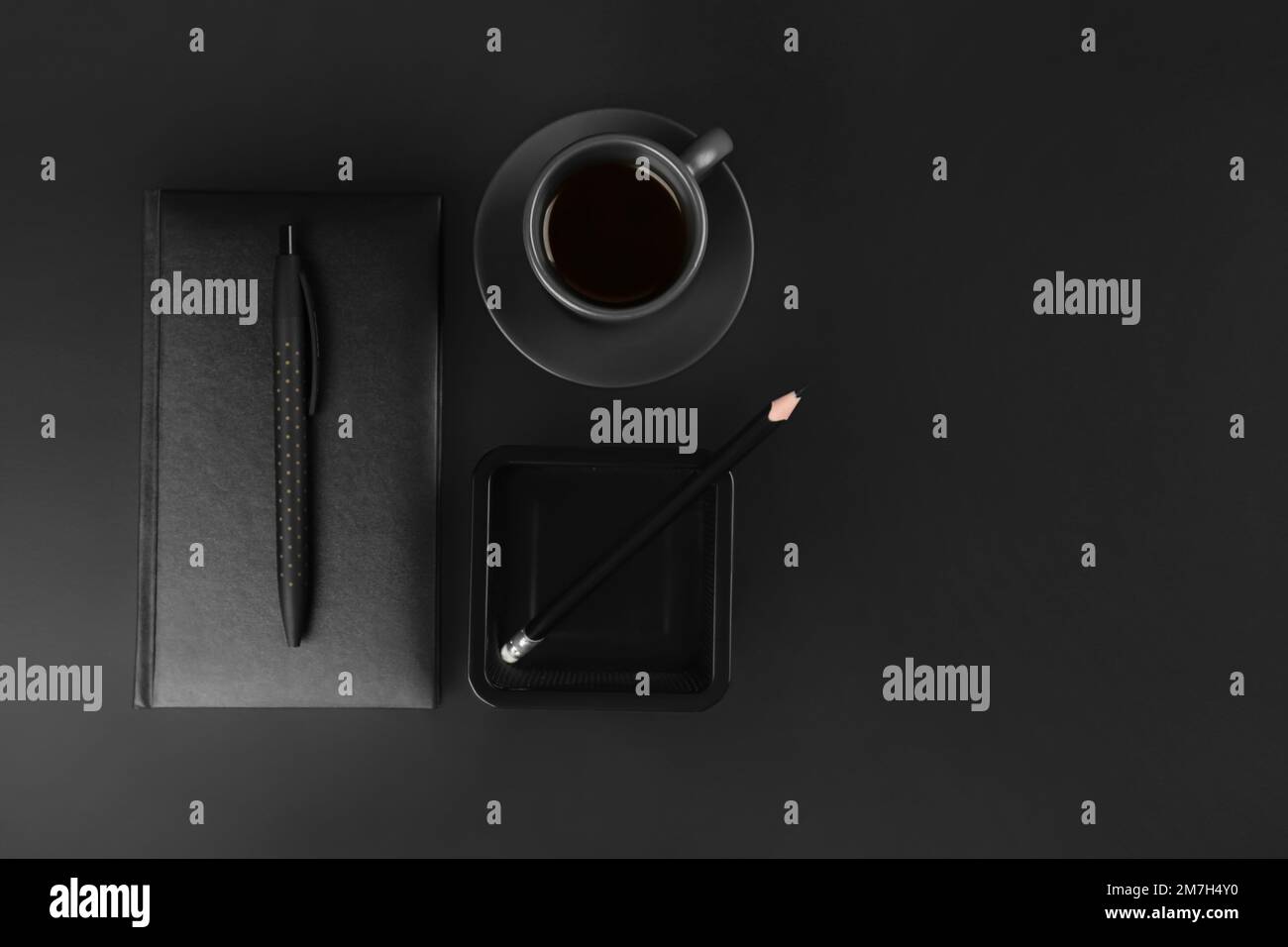 Notebook with pen, pencil holder and cup of coffee on black background ...