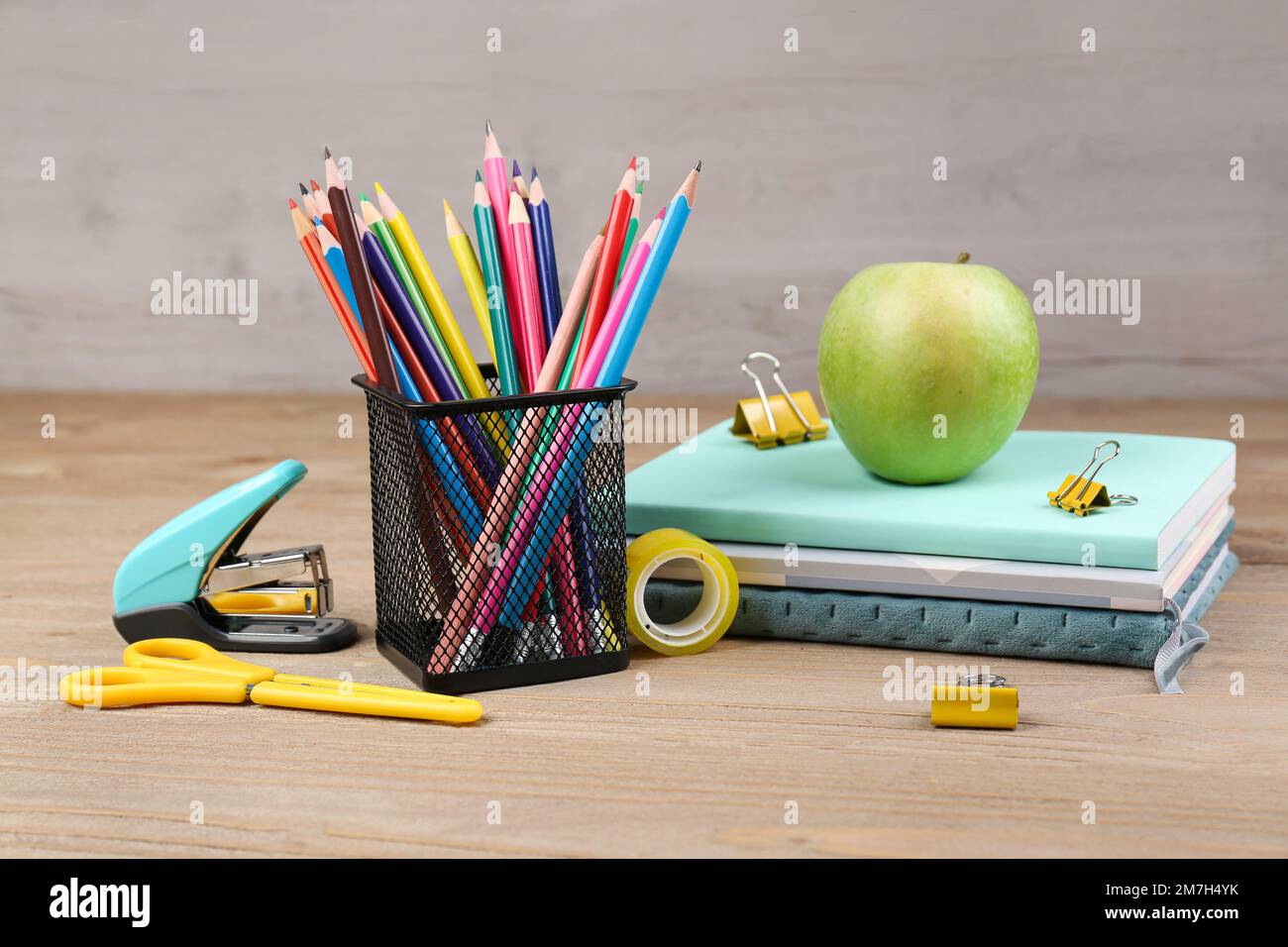 Pencils holder, notebooks with green apple, stapler and scissors on ...