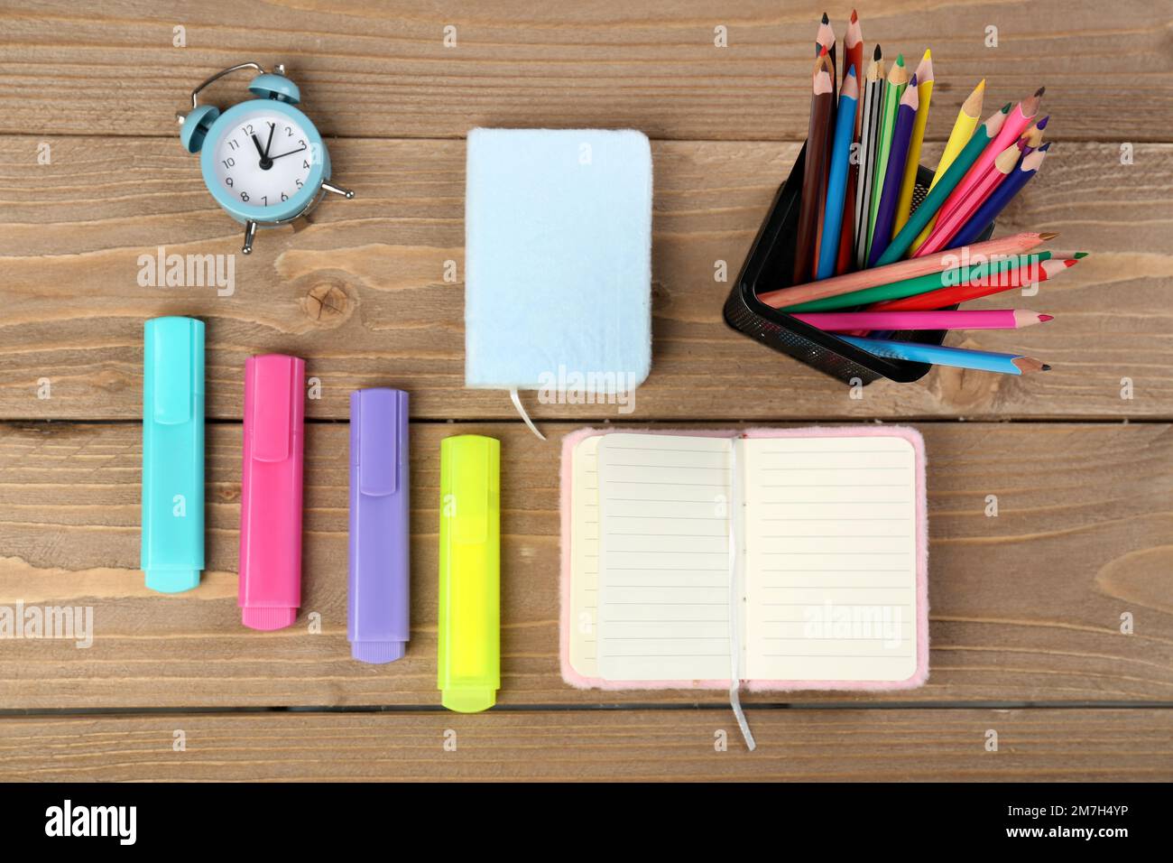 Pencils holder, markers, notebooks and clock on wooden background Stock ...