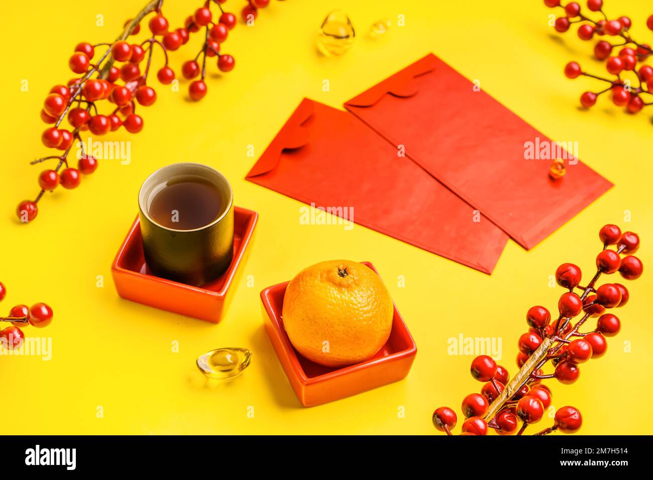 Red envelopes, cup of tea, mandarin and Chinese symbols on yellow ...