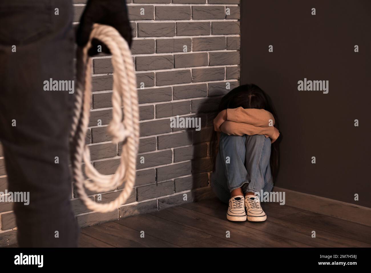 Terrorist with rope and scared little hostage sitting in corner Stock ...