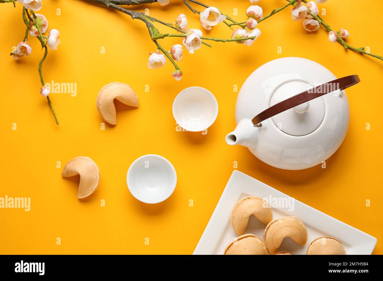 Fortune cookies, teapot, cups and sakura on yellow background. Chinese ...