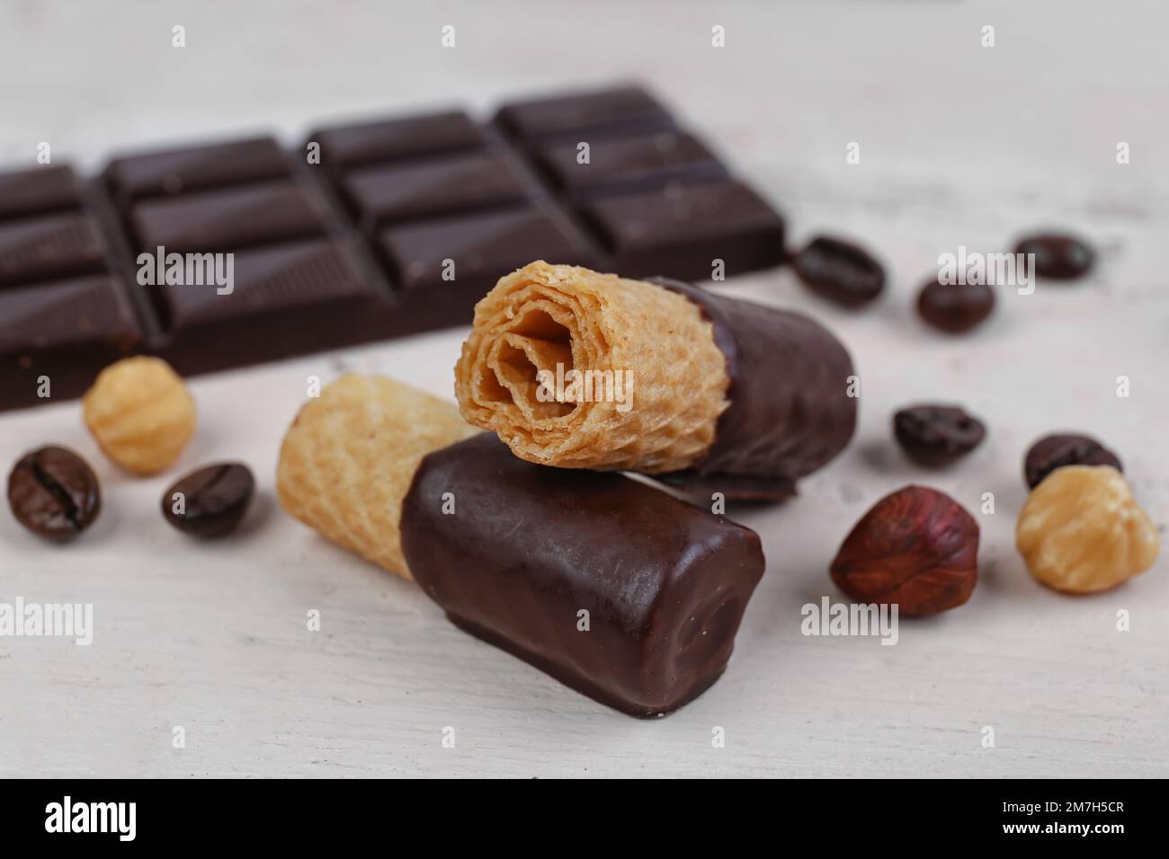 Delicious wafer rolls, nuts, coffee beans and chocolate on light table ...