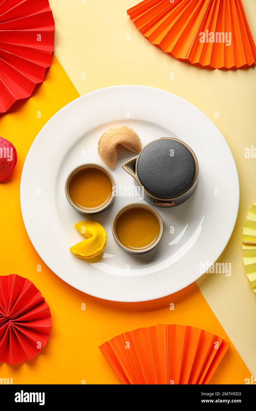 Plate with fortune cookies, teapot, cups and Chinese symbols on color ...