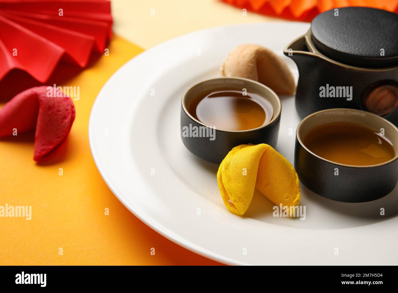Plate with fortune cookies, teapot and cups on color background ...
