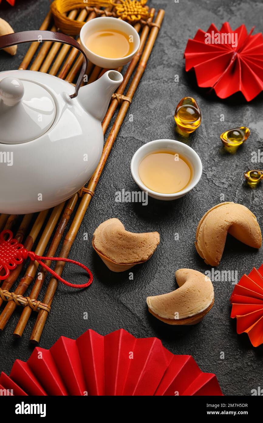 Fortune cookies with teapot, cups and Chinese symbols on dark ...