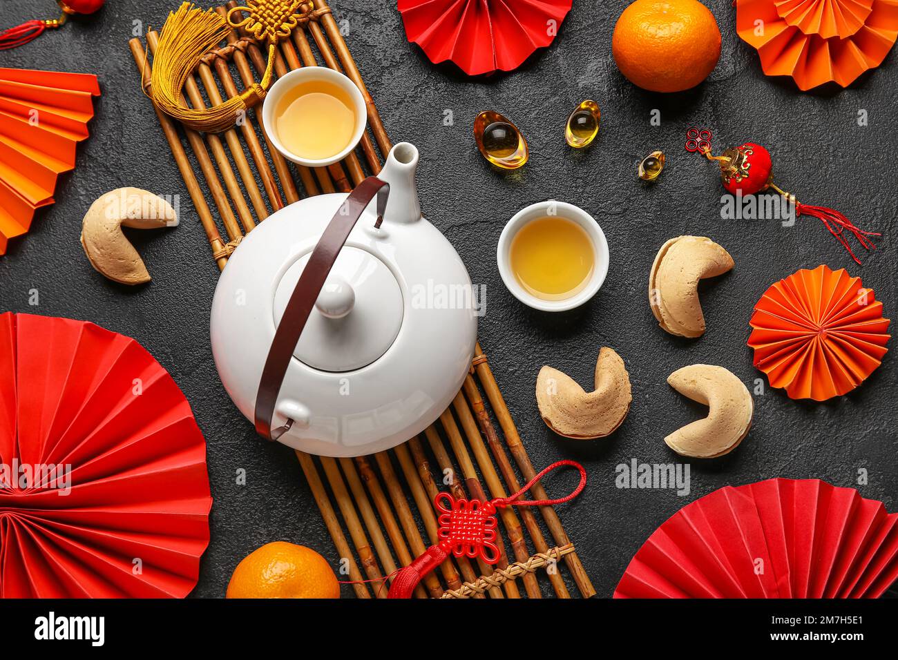 Fortune cookies with teapot, cups and Chinese symbols on dark ...
