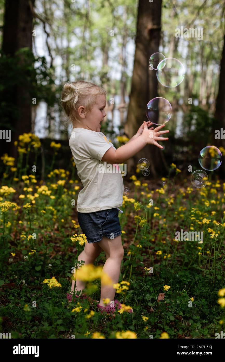 Young child popping bubbles in wild flower field Stock Photo - Alamy