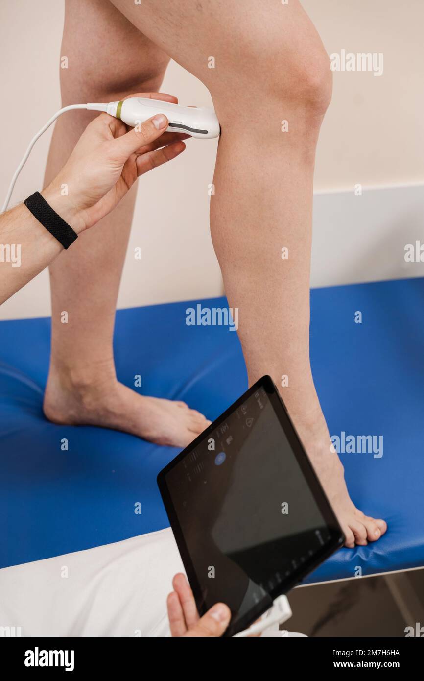 Vascular surgeon examines veins and arteries of legs of girl in medical ...