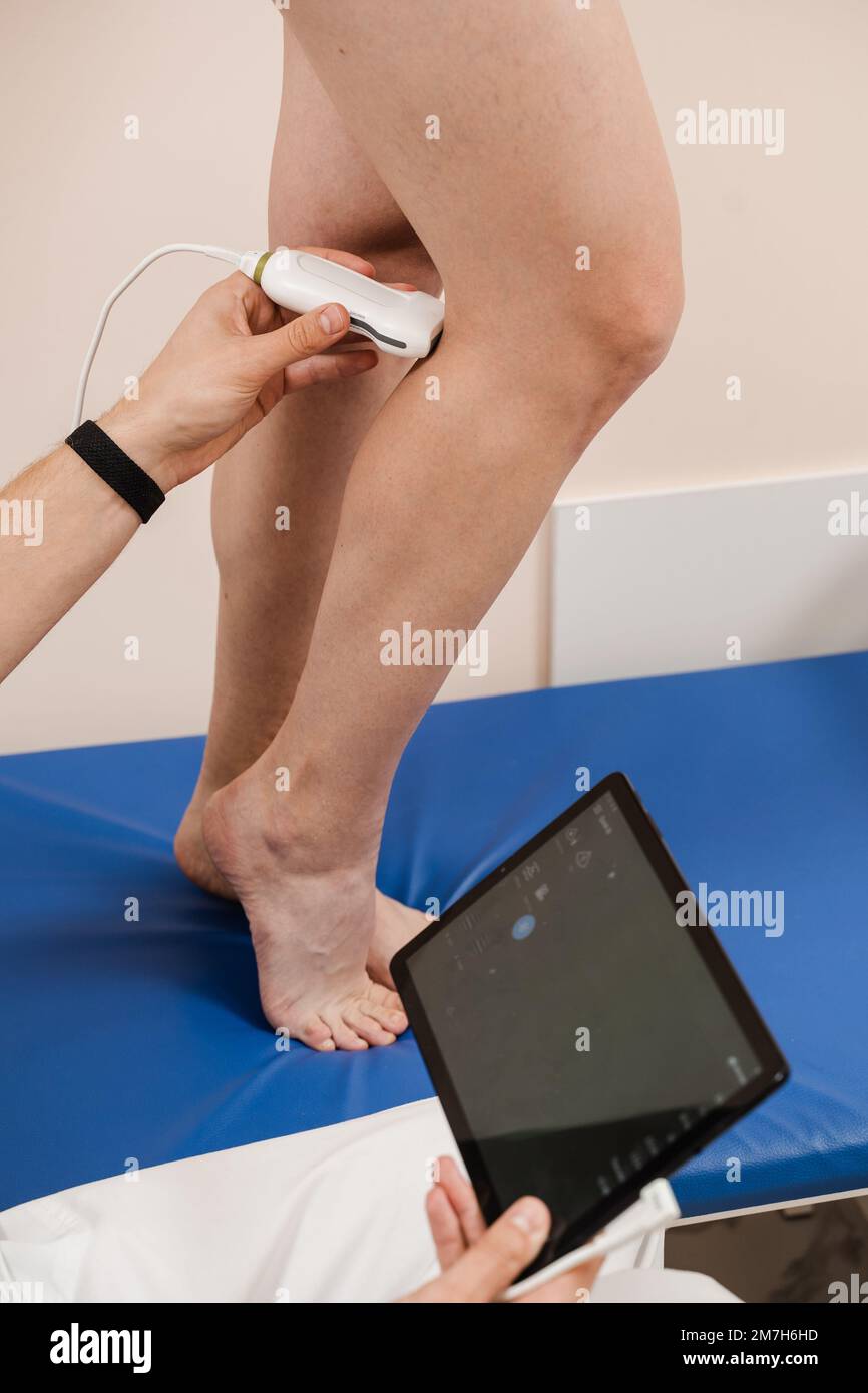 Vascular surgeon examines veins and arteries of legs of girl in medical ...