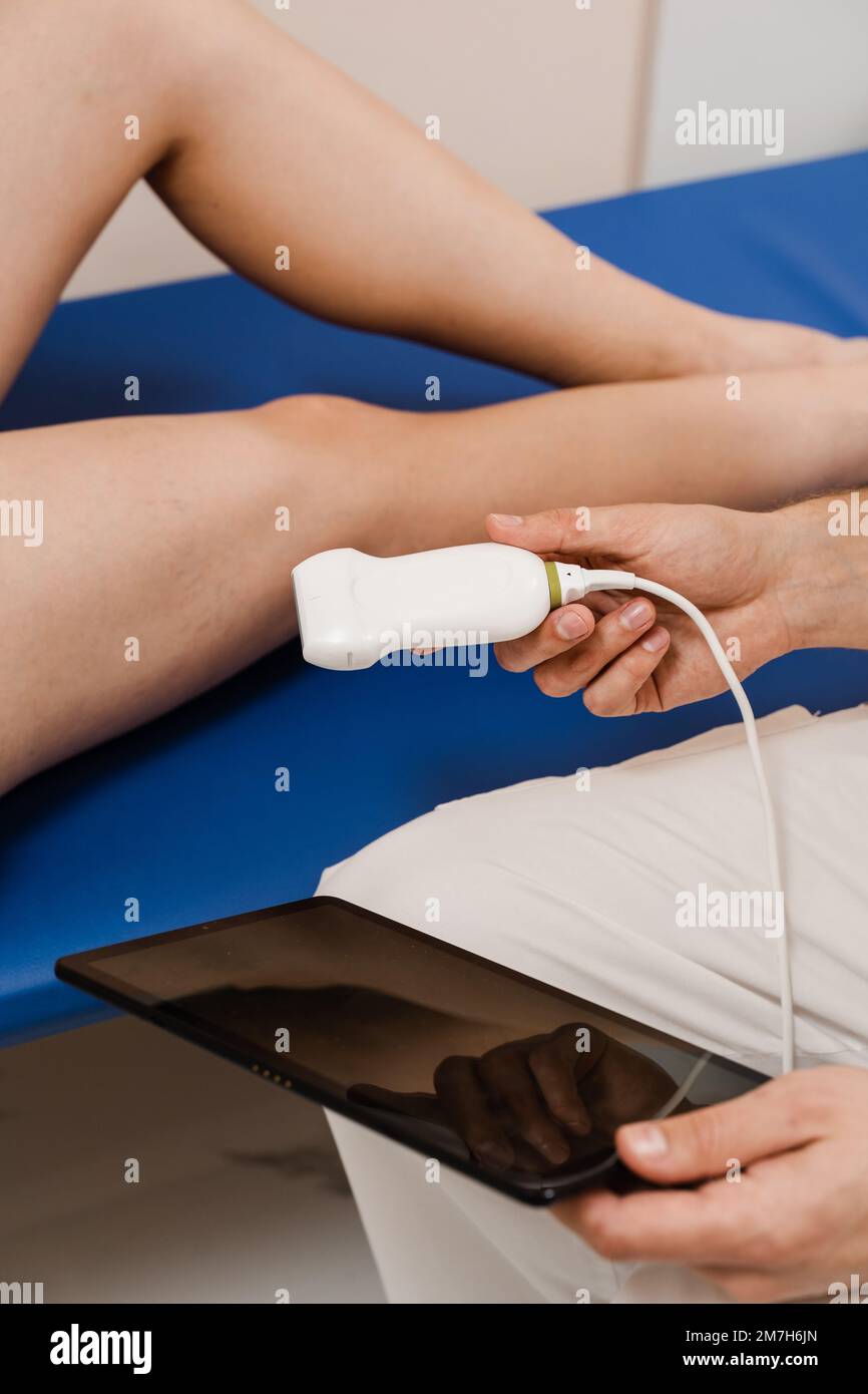 Vascular surgeon examines veins and arteries of legs using ultrasound ...