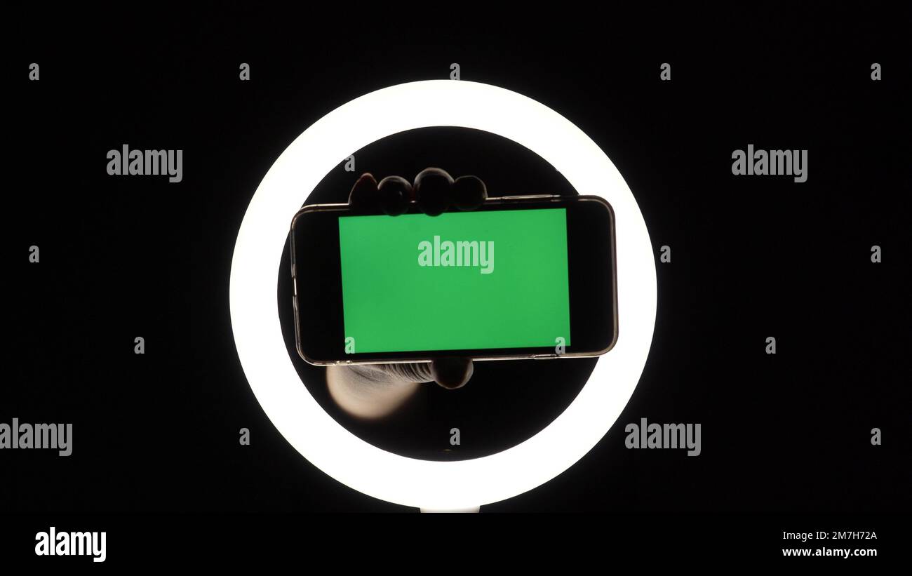 female hands show the phone close-up on a black background. green ...