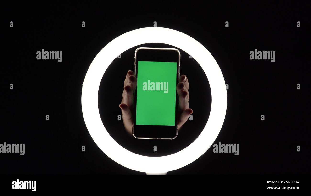 female hands show the phone close-up on a black background. green ...