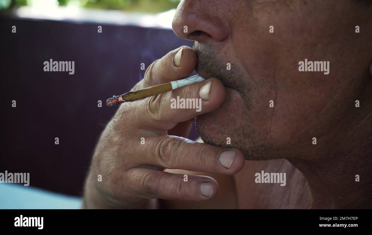 A man smokes a cigarette between work. Close-up. A lot of smoke ...