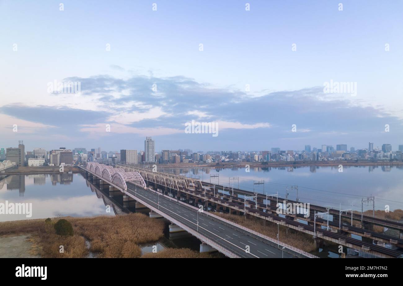 Empty vehicle and railroad bridges over river by city at dawn Stock ...