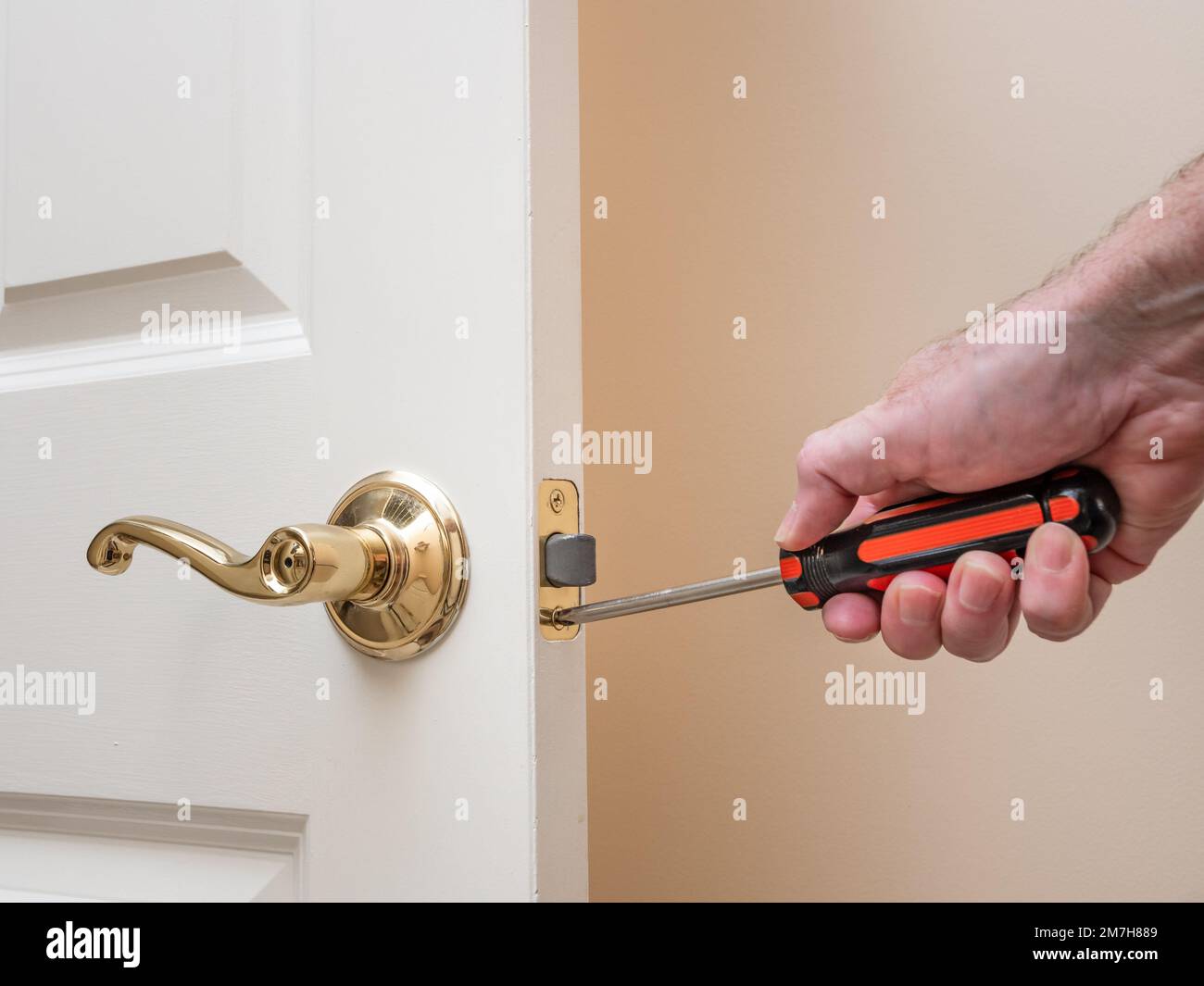 Carpenter repairing door latch. Handyman using screwdriver to install ...