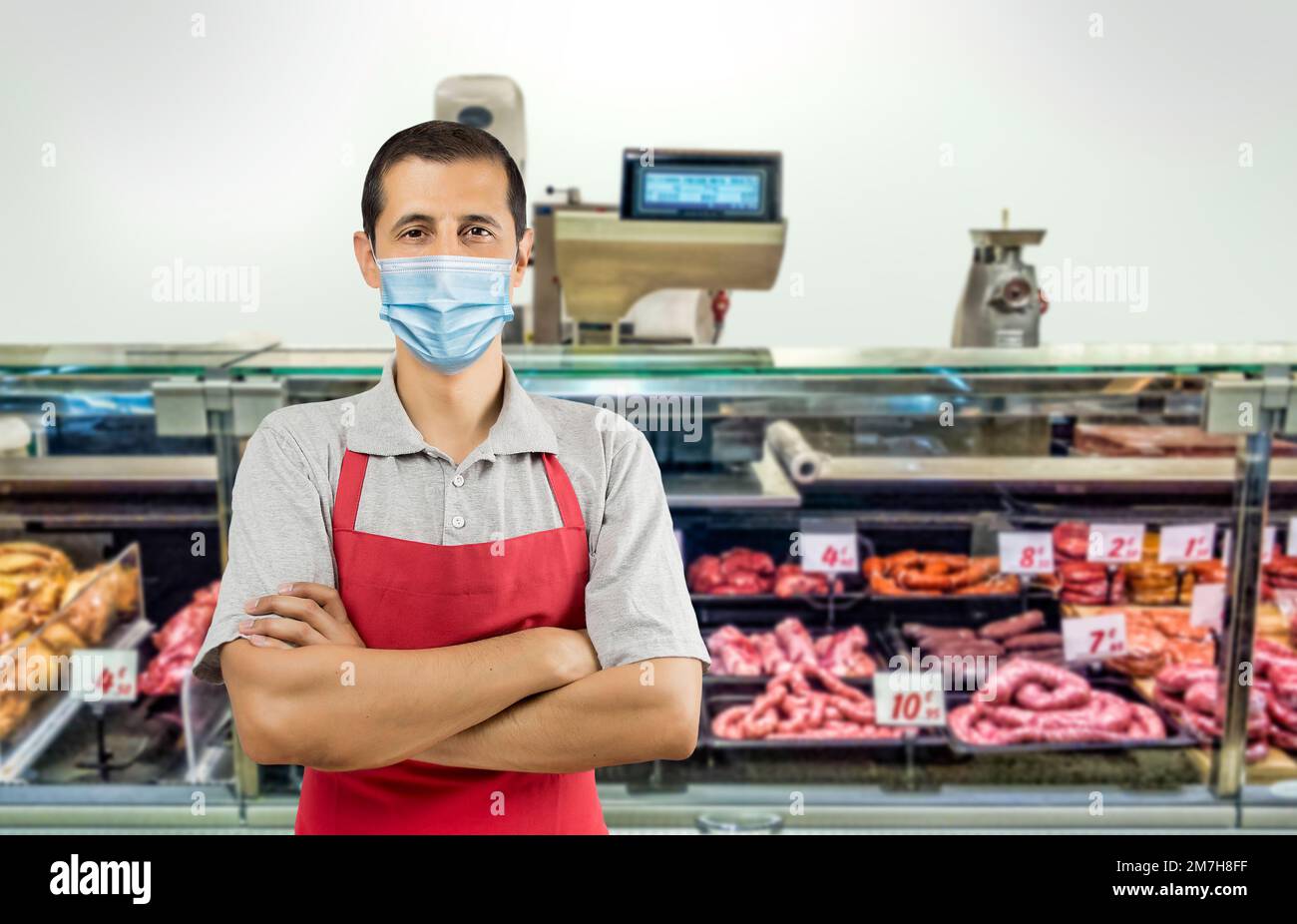 Portrait of a butcher with face mask with his arms crossed and smiling ...