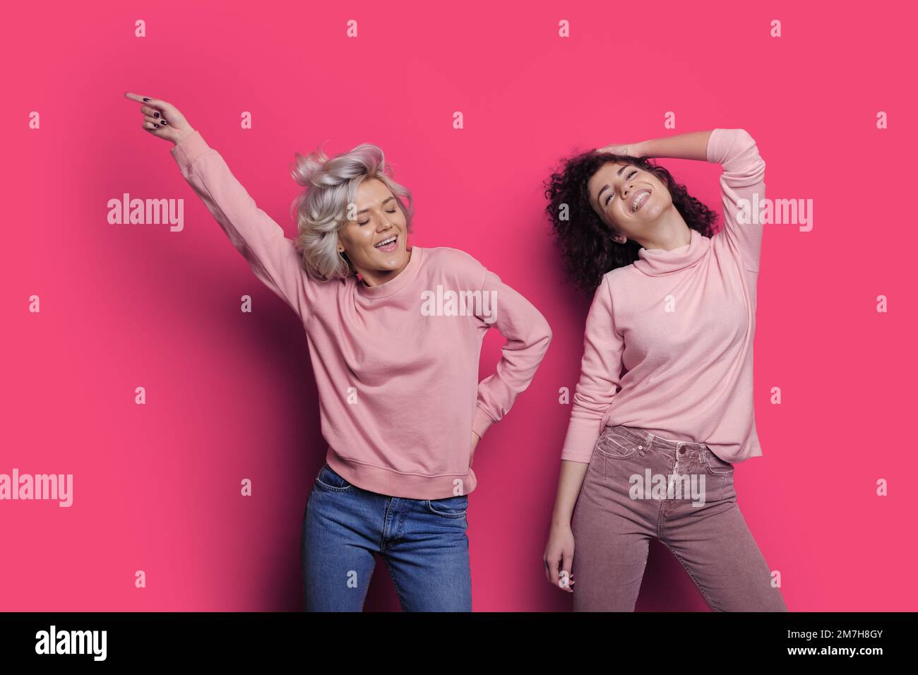 Energetic two women dancing waving hands with smile on face, posing ...