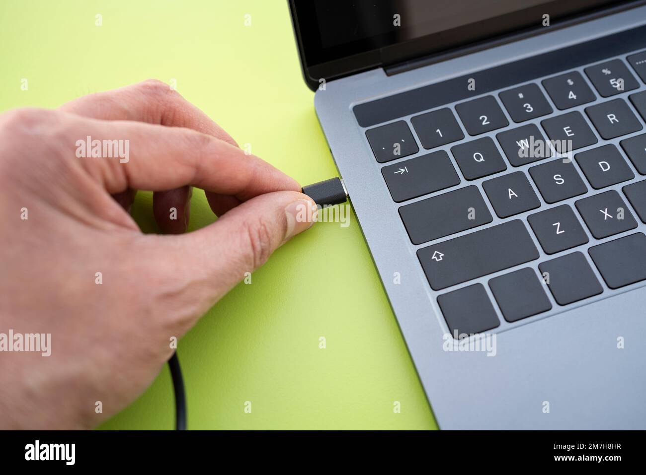 Close up of a man hand connecting a usb-c cable on a laptop with green ...