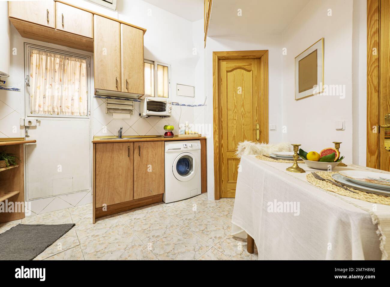 Conventional open plan kitchen with light wood cabinets with white ...