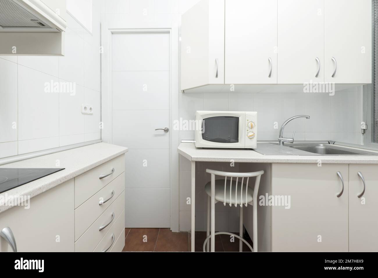 Corner of a humble conventional kitchen with white cabinets and ...