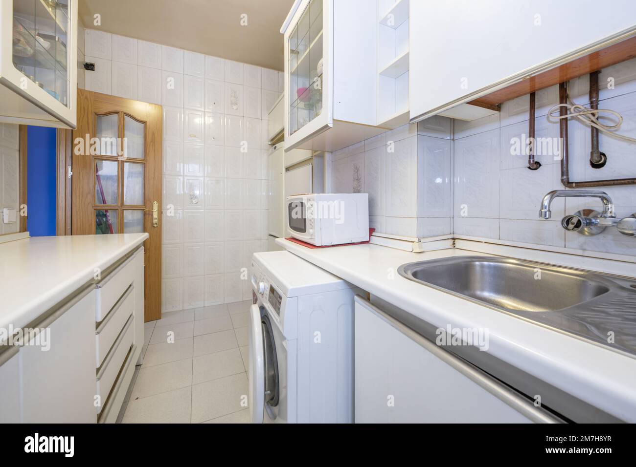 Kitchen with white furniture, countertops and appliances, copper water ...