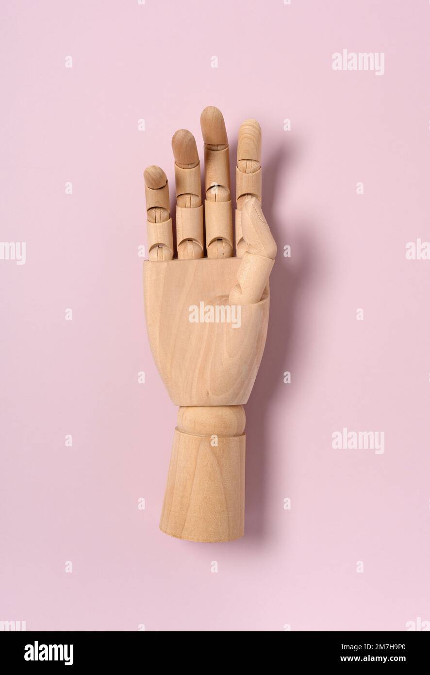 Wooden mannequin hands placed on pink background. View from directly ...