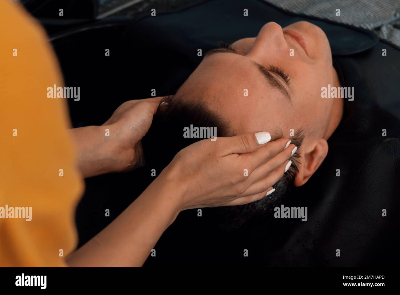 Closeup caucasian man getting hair wash by professional hairdresser ...