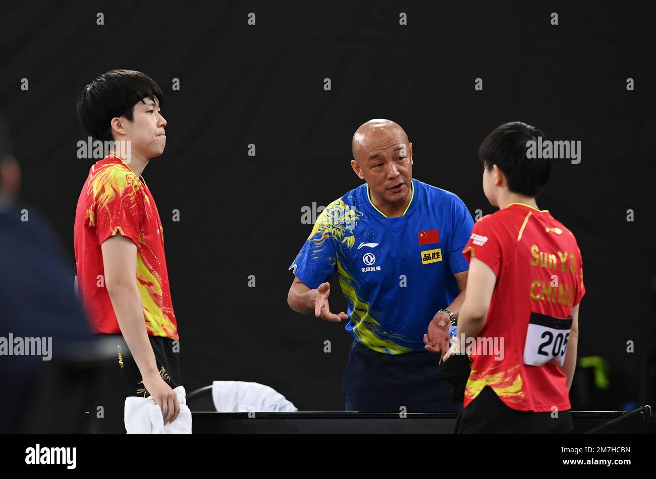 Doha, Qatar. 9th Jan, 2023. Coach Xiao Zhan (C) instructs Wang Chuqin ...