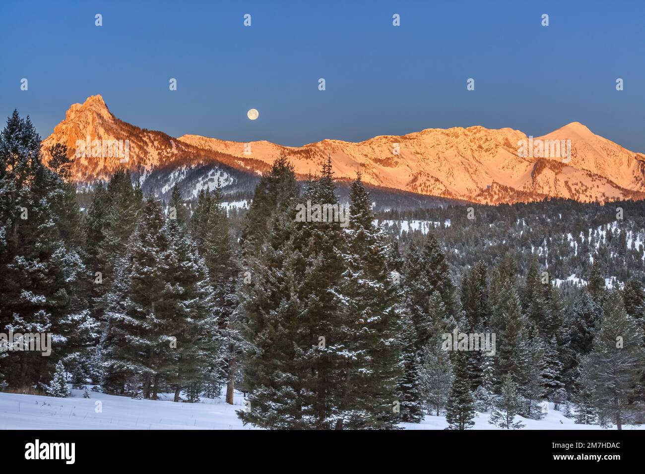 full moon setting over the bridger mountains in winter near bozeman ...