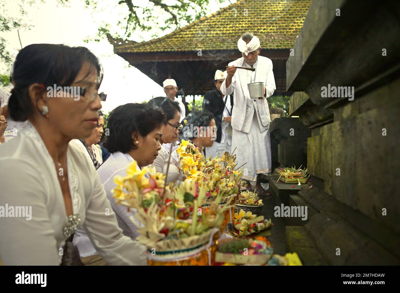 A Balinese Hindu priest splashing holy water to spiritual offerings ...