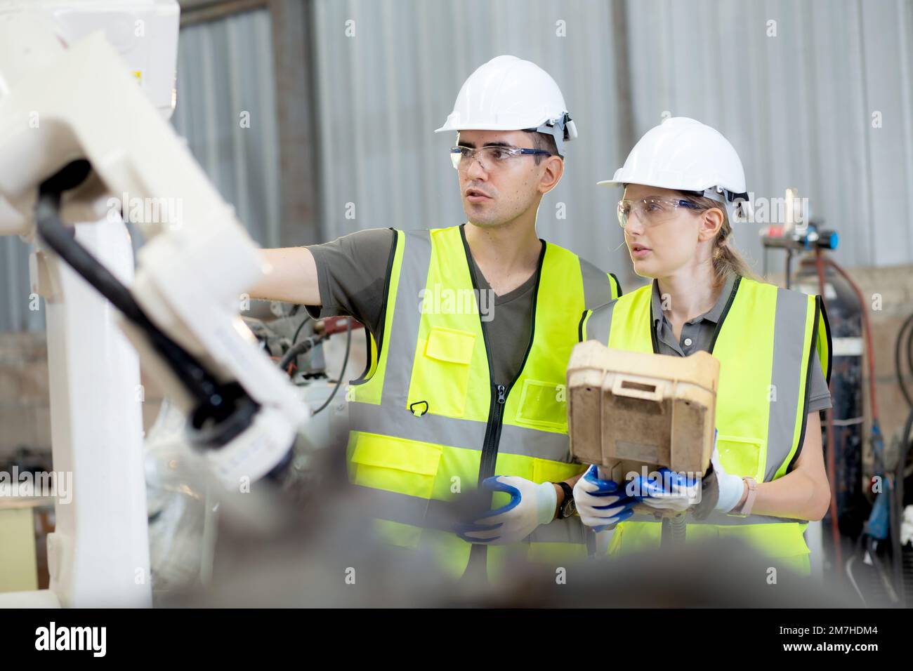 Engineer man and woman talking and explaining about robot arms ...