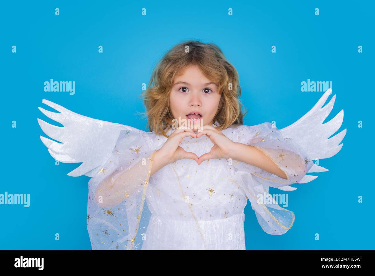 Little angel. Portrait of cute kid with angel wings isolated on blue ...