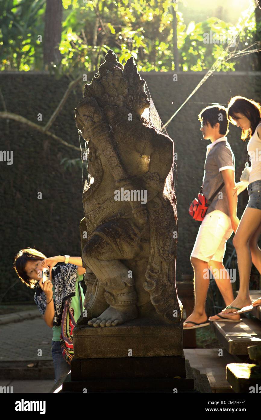 A woman tourist photographing a dvarapala (door guardian) statue at ...